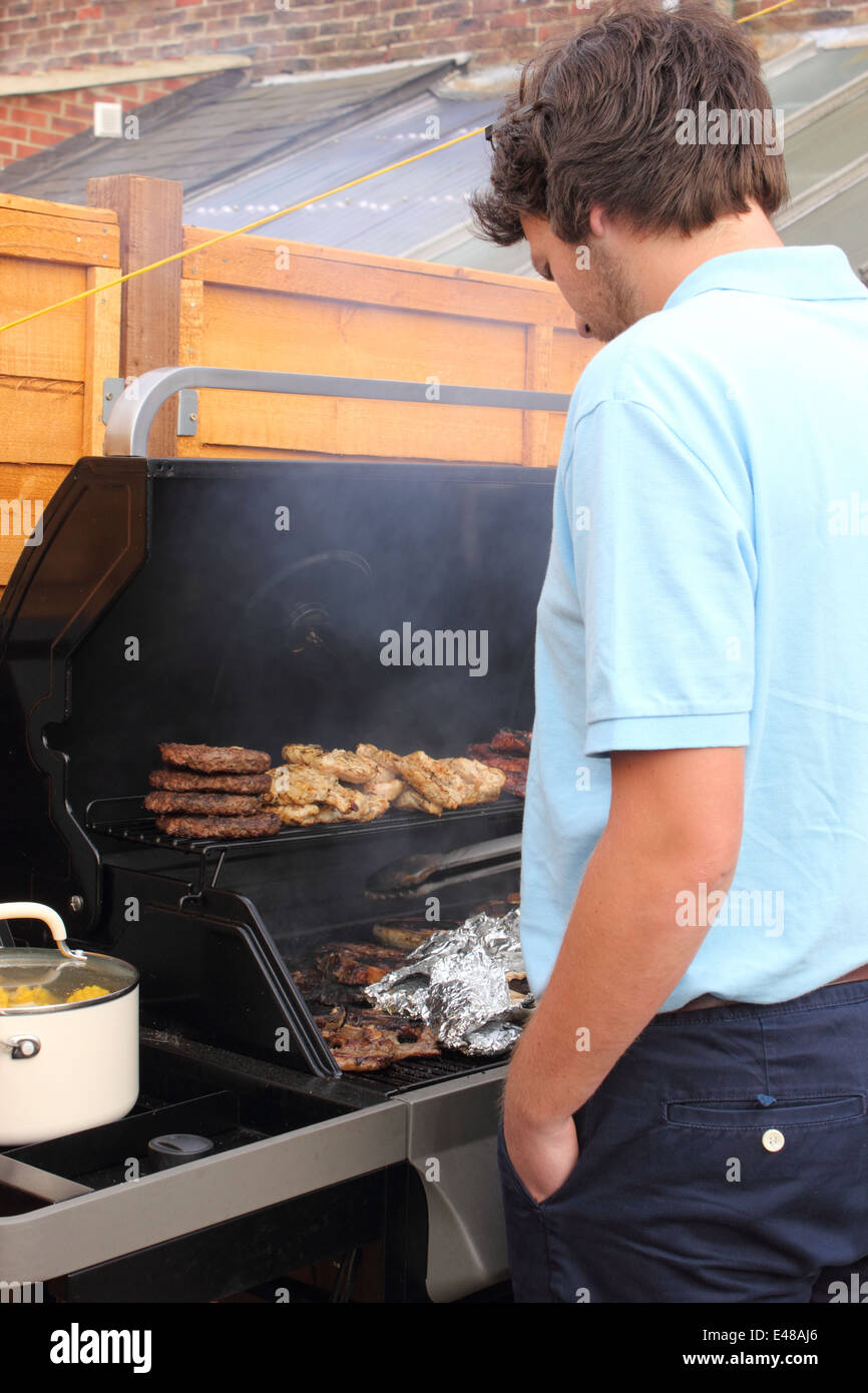 A young man cooking on the bbq Stock Photo - Alamy