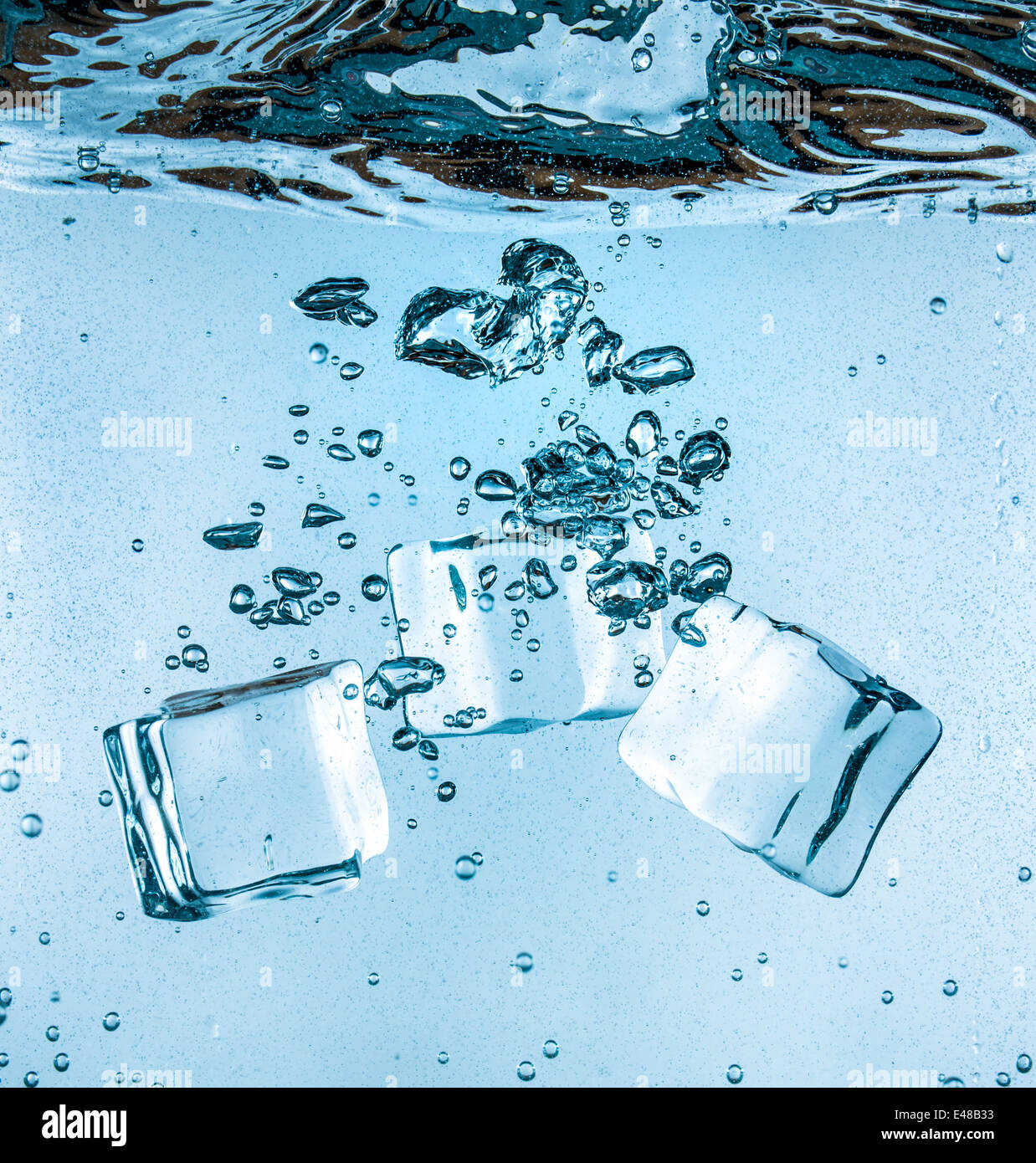 Ice cubes falling into the water sinking to the bottom. Abstract ...
