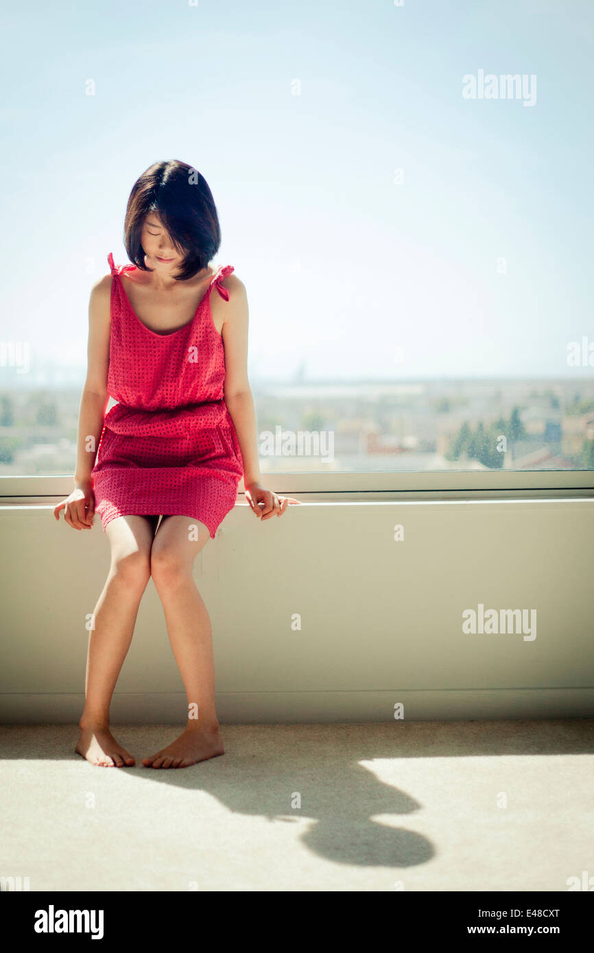 Young woman sitting on ledge Stock Photo - Alamy