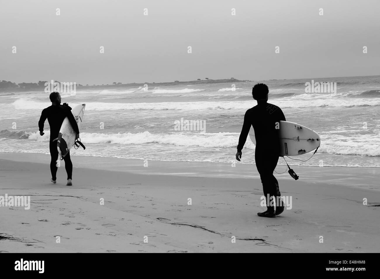Surfers holding surfboards getting ready to go dive into the surf, on ...
