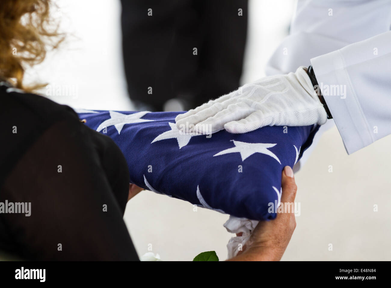 active navy representatives giving the US flag to the widow at a ...