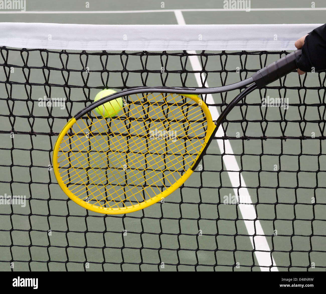 Tennis ball goes into net with racket and players hand behind ball ...