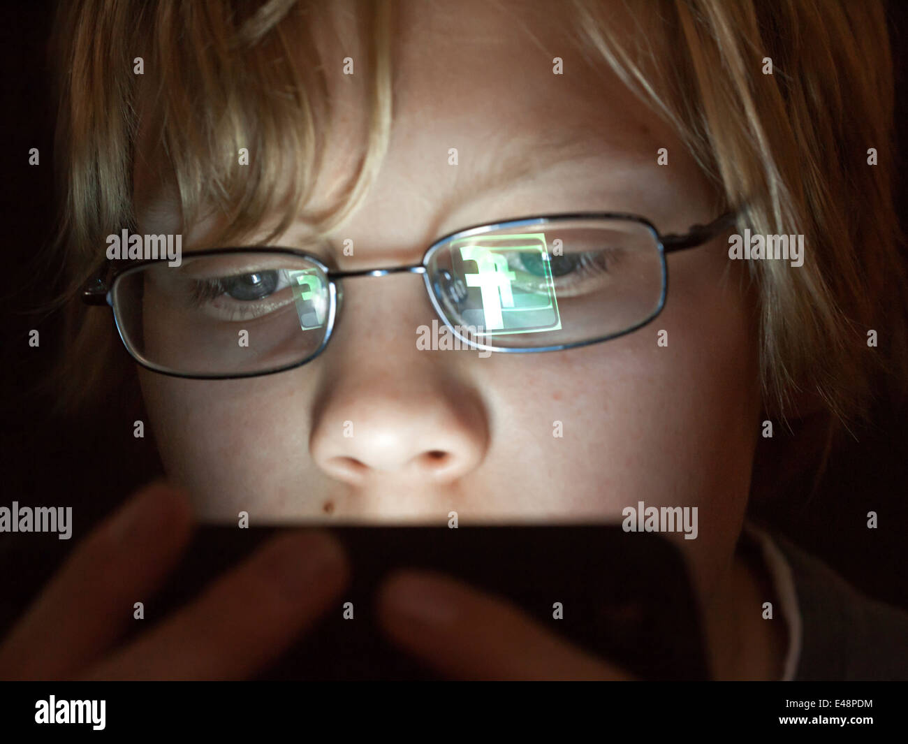 A teenage boy is surfing the Internet using his iPhone with the ...