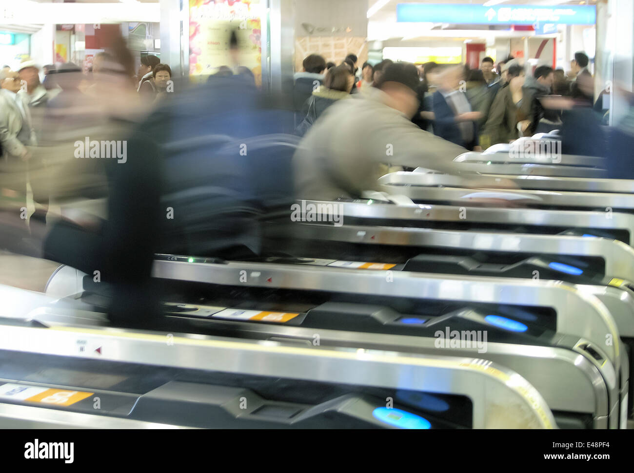 Commuters are rushing through turnstiles at the Shinjuku subway station ...