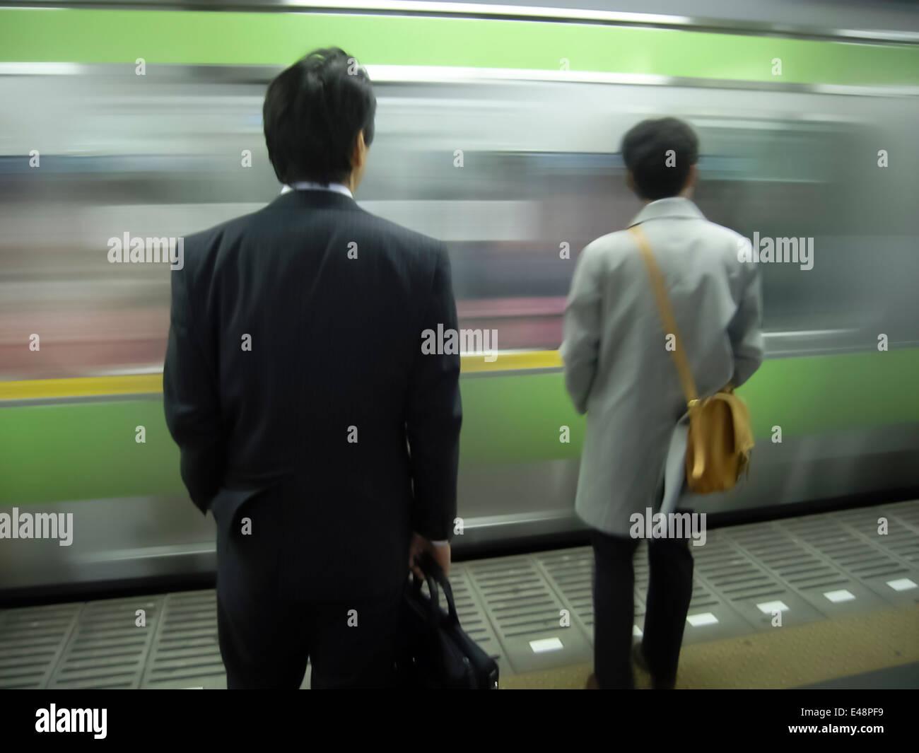 Tokyo commuters wait on the platform for an incoming subway train Stock ...