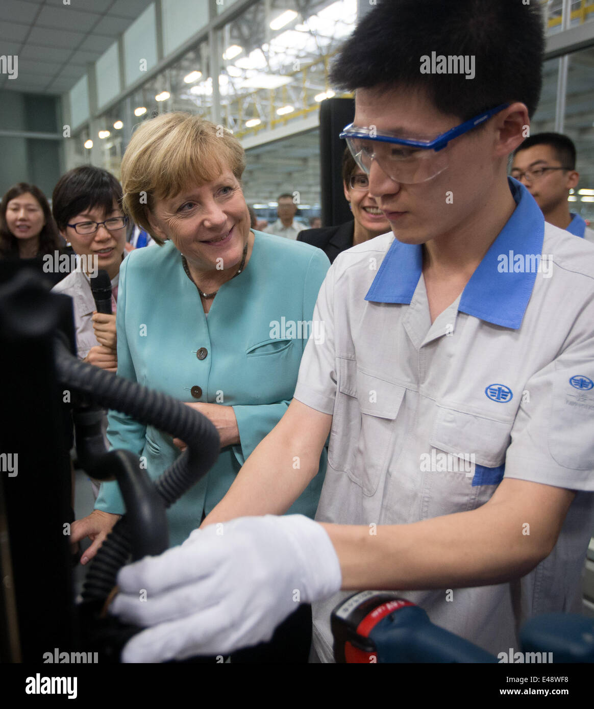 German Chancellor Angela Merkel (L) looks on as an apprentice performs ...