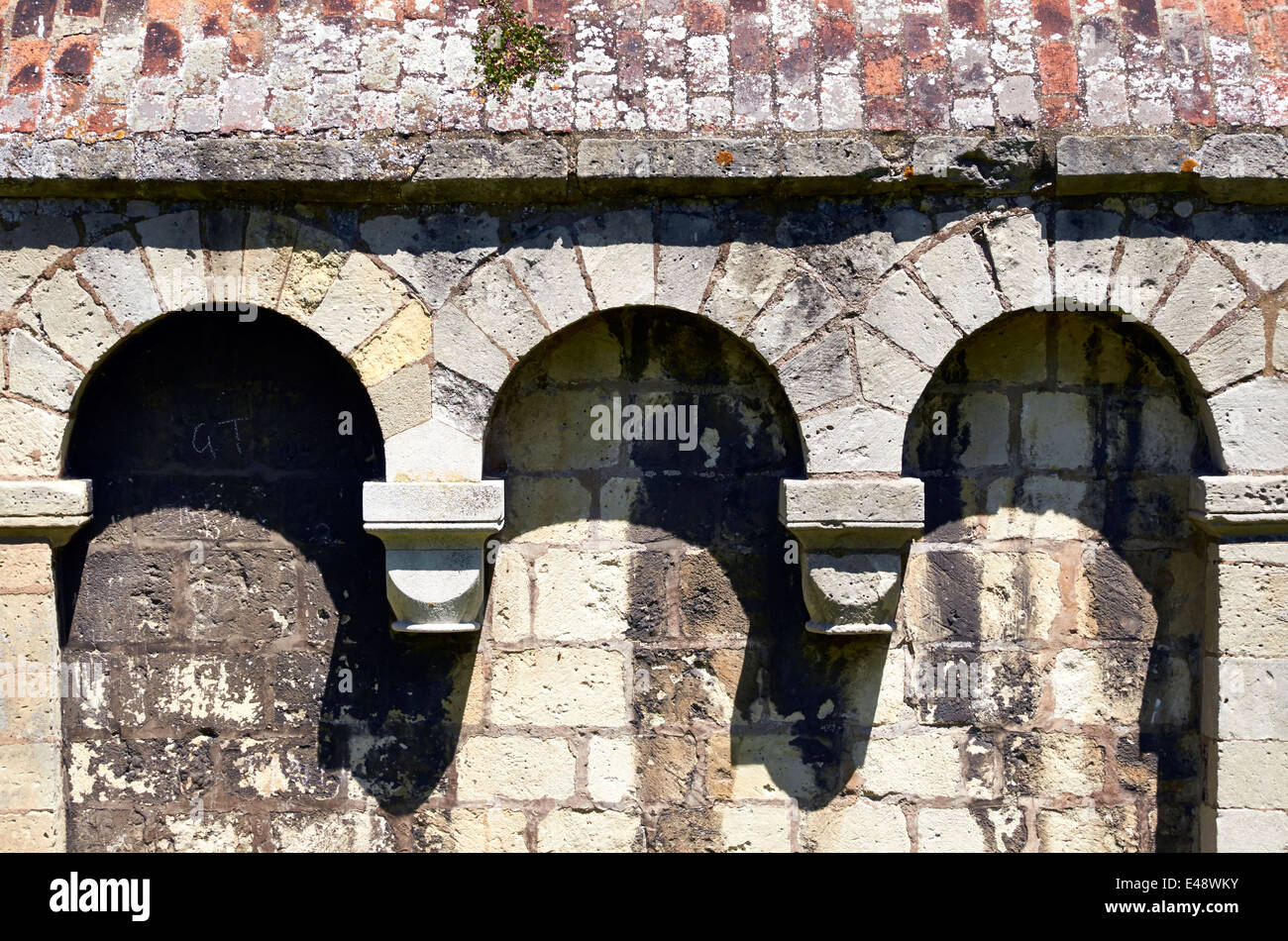 Medieval stonework and three Romanesque arches over a niche in the wall ...