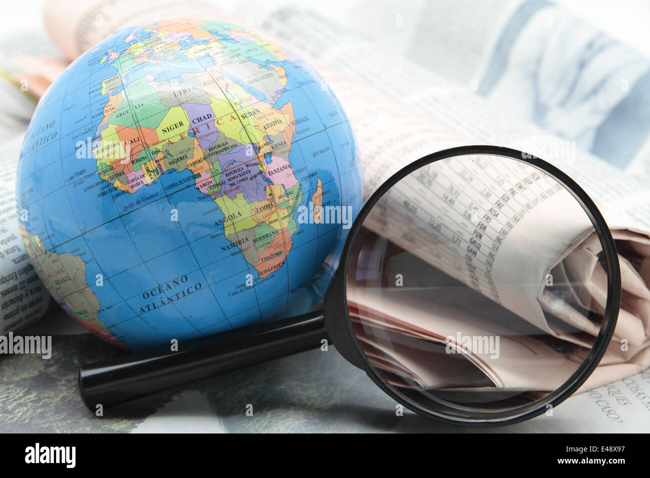 globe and magnifying glass over newspapers Stock Photo - Alamy