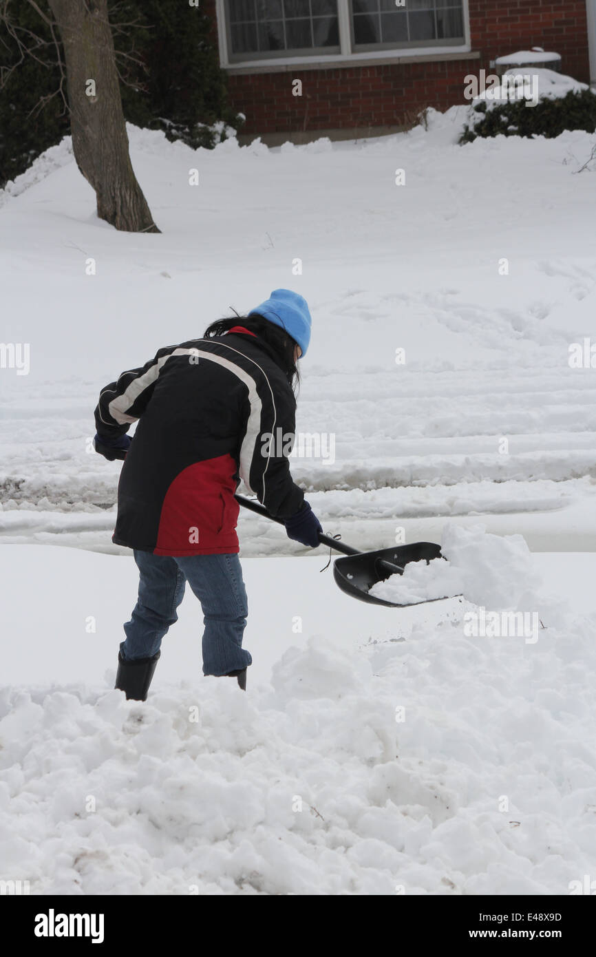 Lady shoveling the deep snow off her driveway after a snow storm Stock ...