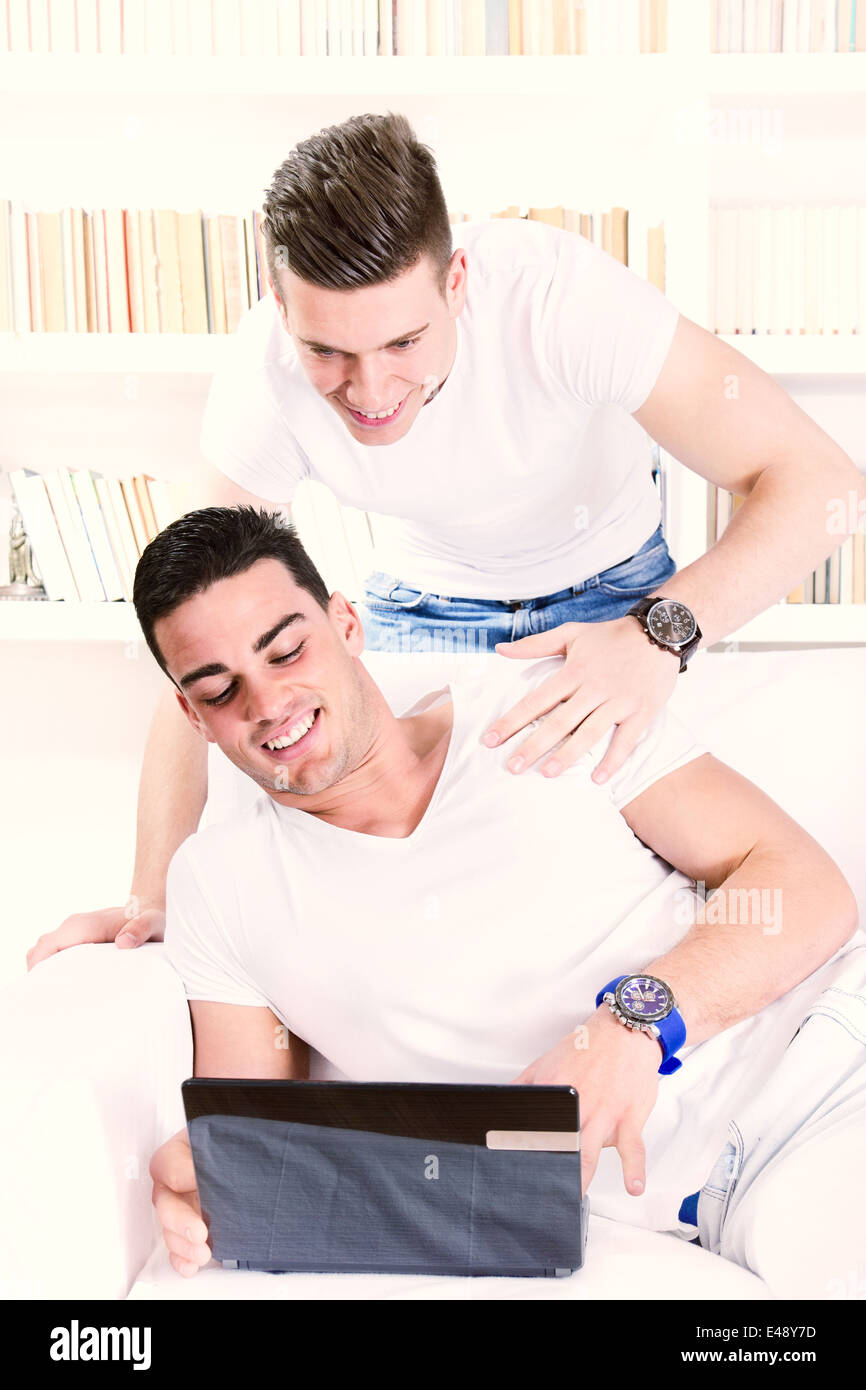 two cheerful young people looking at laptop and having fun over the ...
