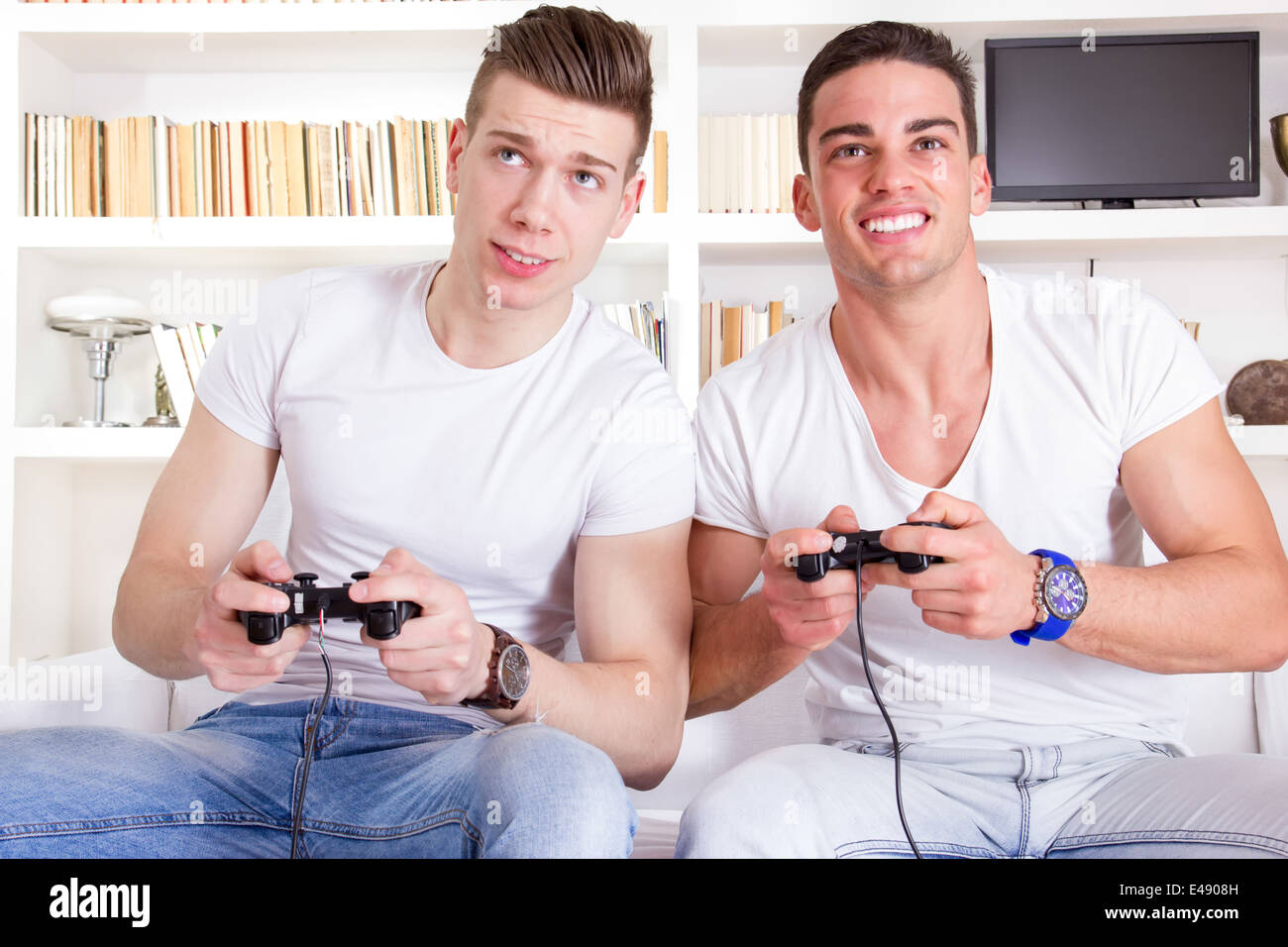 two male friends playing video game with controllers at home Stock ...