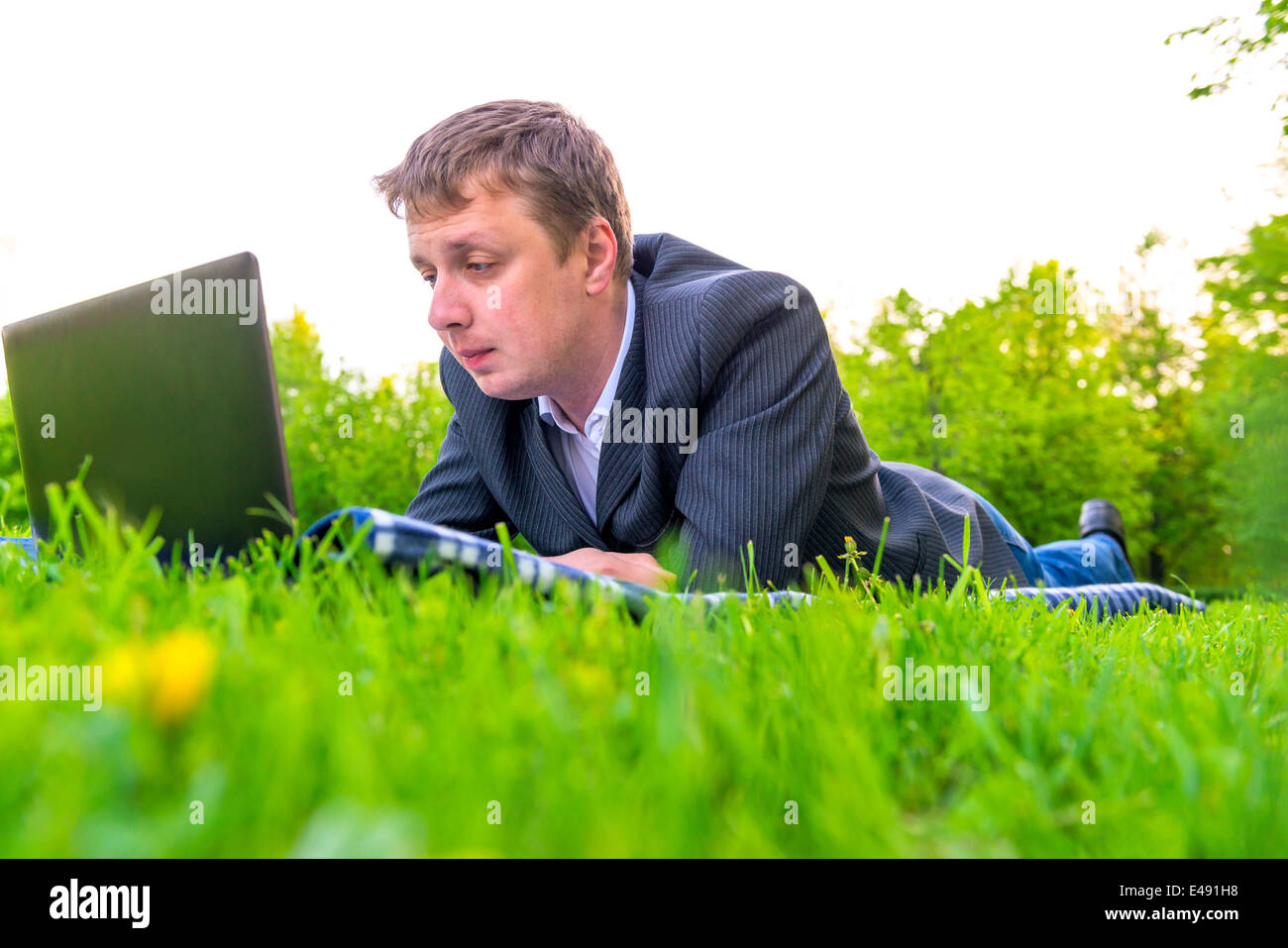 man working with laptop lying on the lawn Stock Photo - Alamy