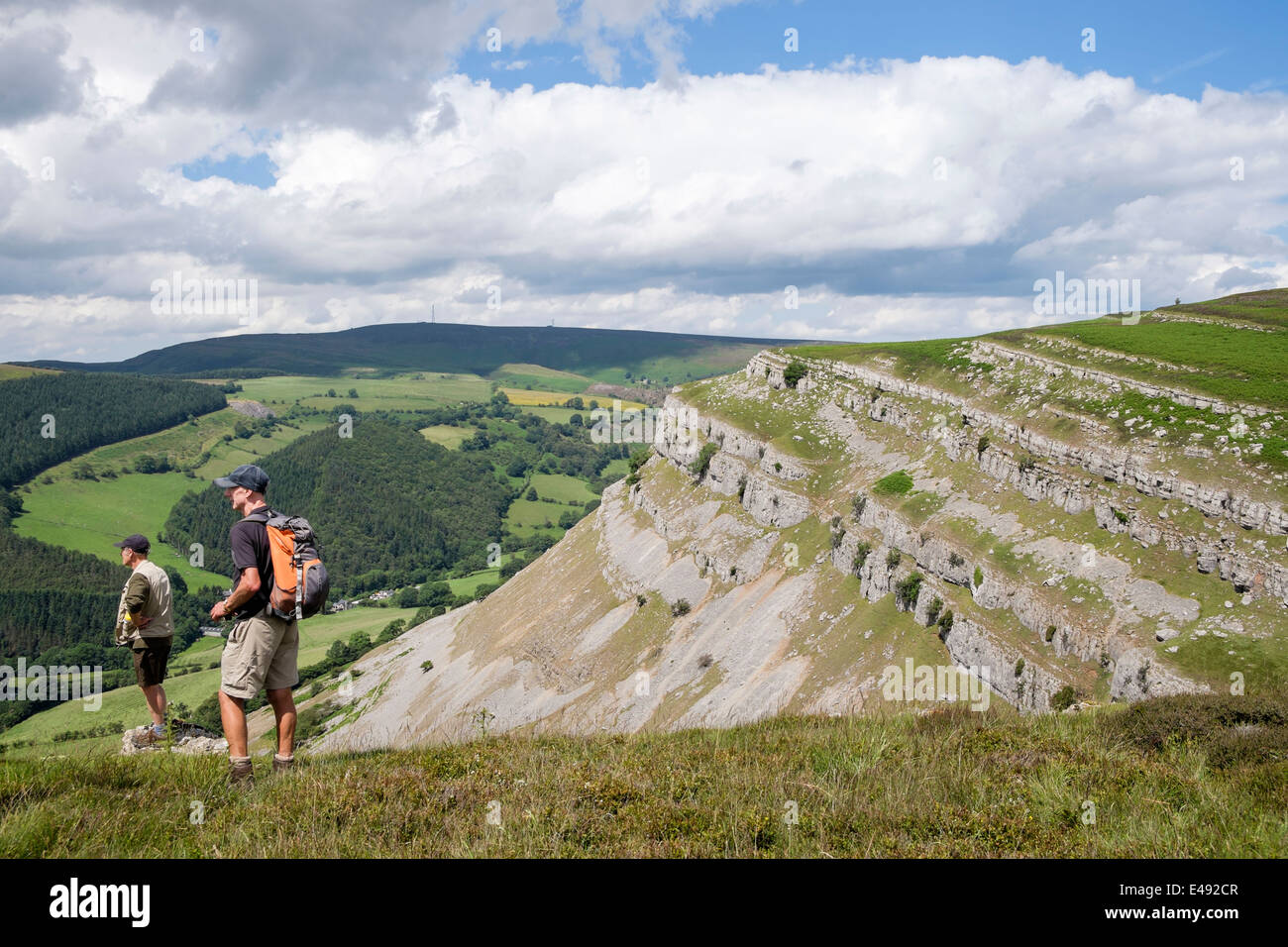 Walkers on Eglwyseg mountain with limestone escarpment above valley in ...