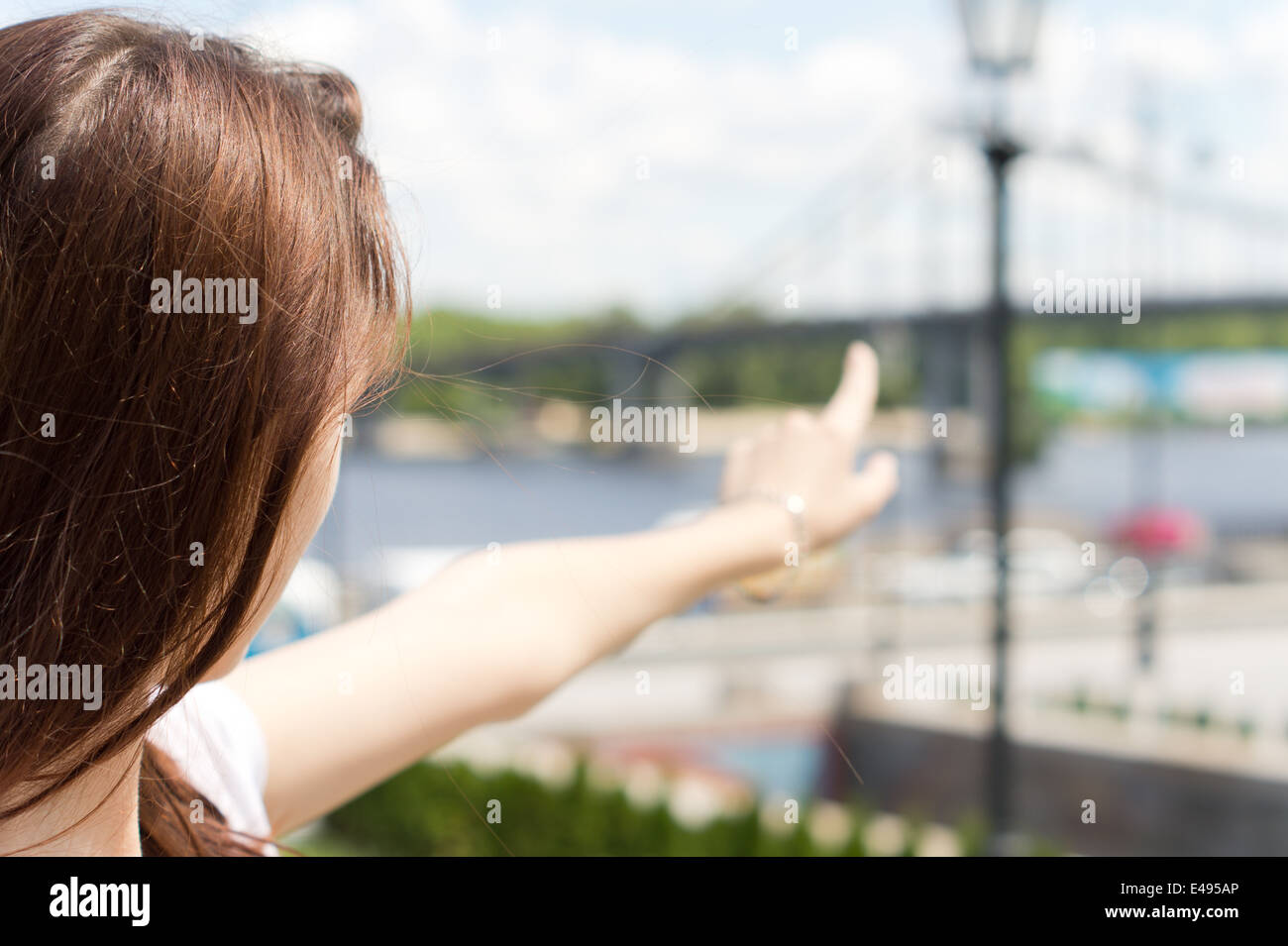 Side rear view of a brown haired female tourist pointing towards a ...
