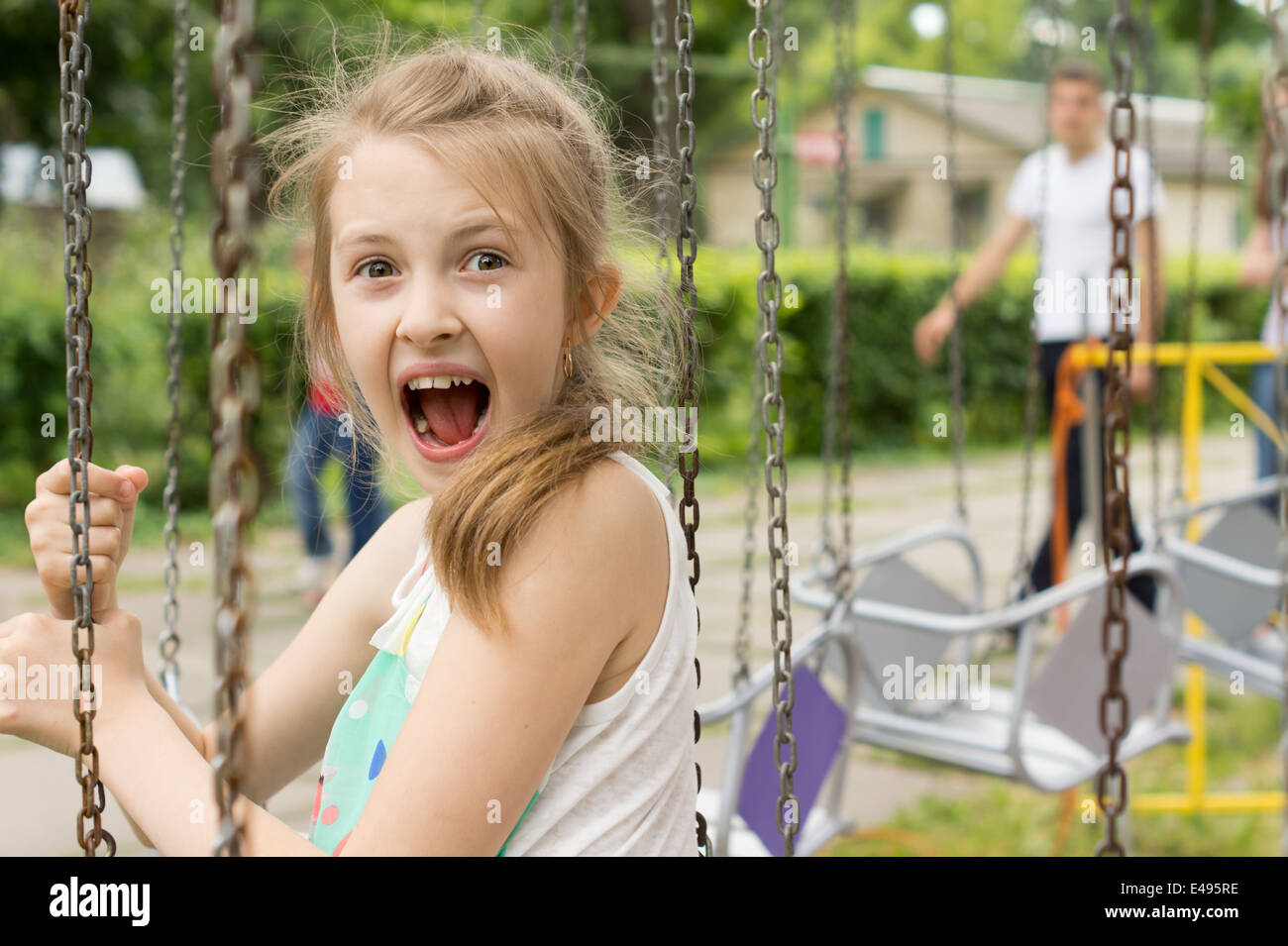 Excited little girl on a ride at the fairground screaming in delight ...