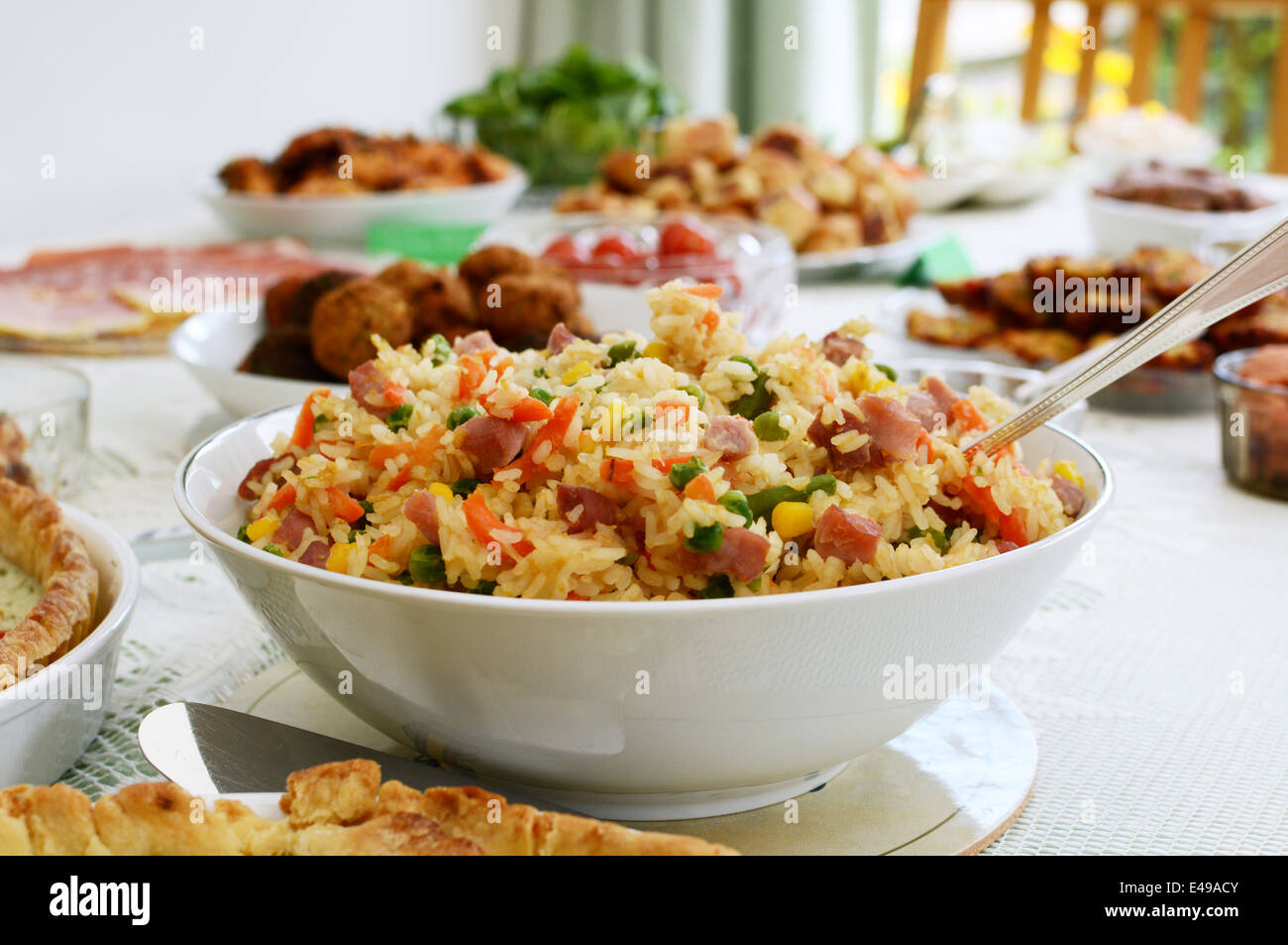 Bowl of gammon and mixed vegetable rice salad with other party food on ...