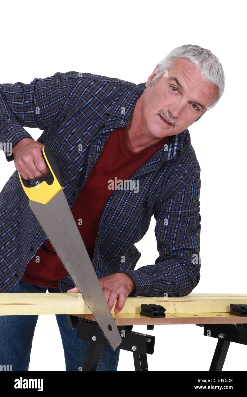 Elderly handyman sawing wood Stock Photo - Alamy