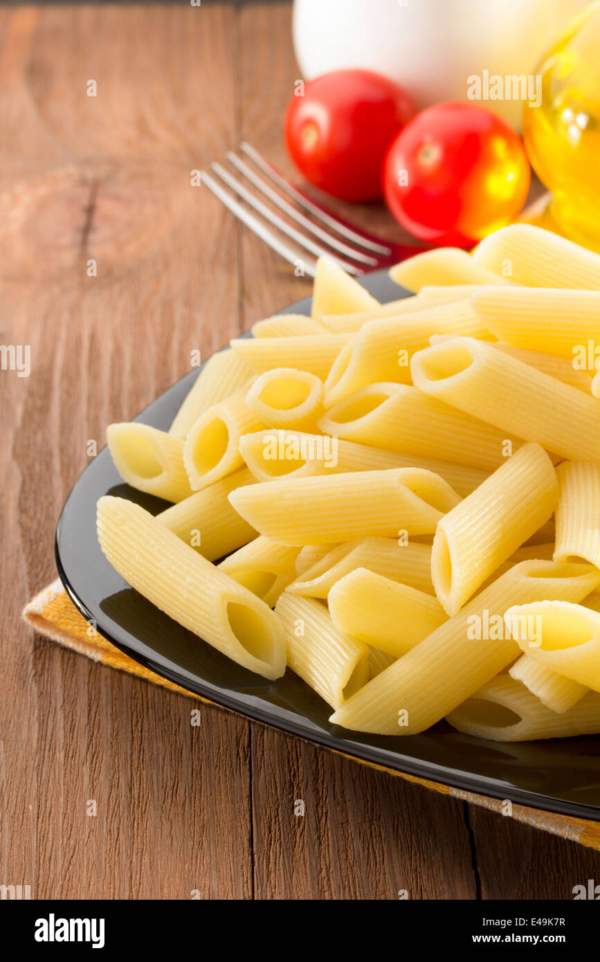 pasta Penne in plate on wooden background Stock Photo - Alamy