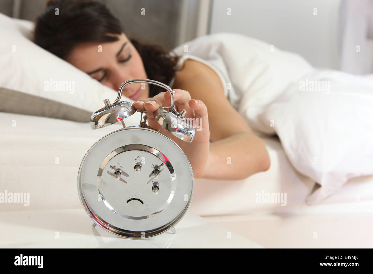 Woman turning off alarm clock Stock Photo - Alamy