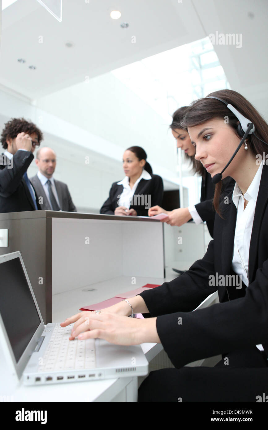 Woman working on a busy reception desk Stock Photo - Alamy
