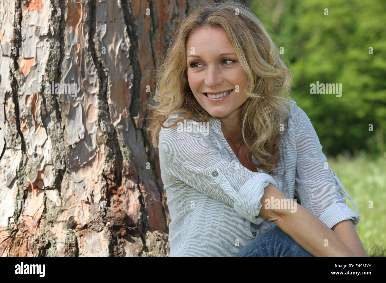 woman sitting against a tree Stock Photo - Alamy
