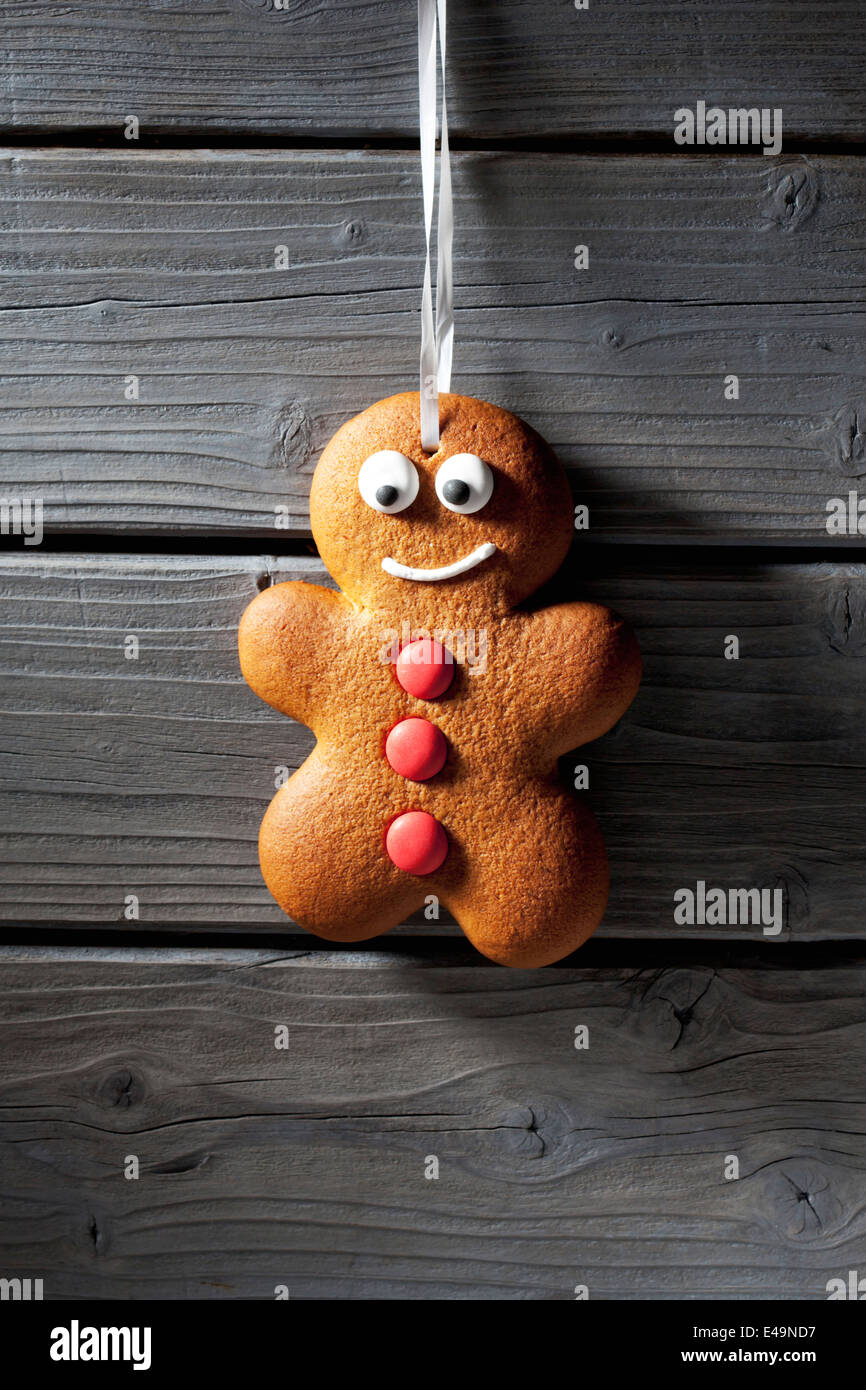 Smiling gingerbread man hanging in front of grey wooden wall Stock ...