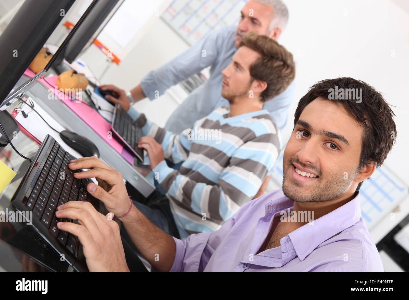 Smiling young man using a computer Stock Photo - Alamy