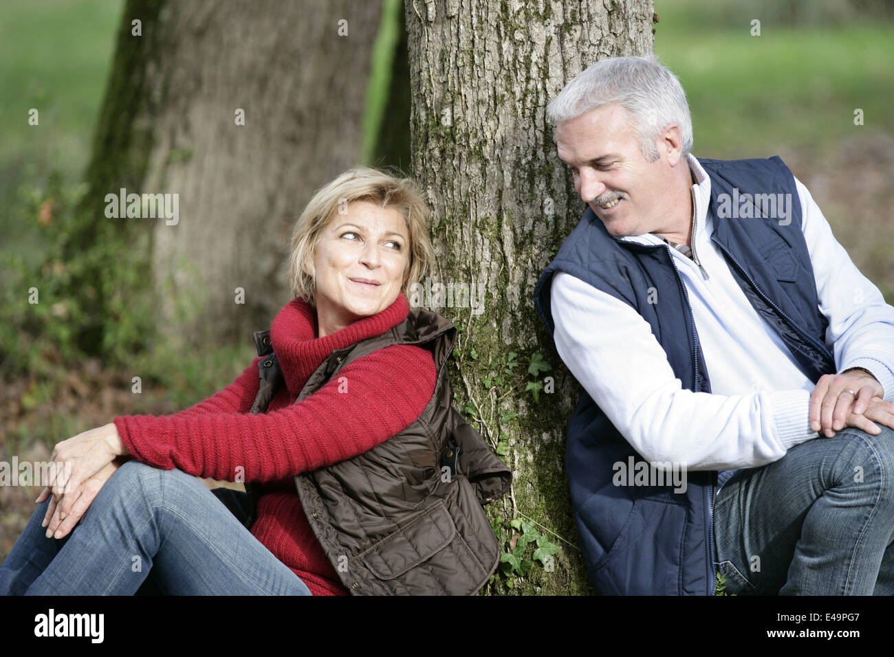 Middle-aged couple sat by tree Stock Photo - Alamy