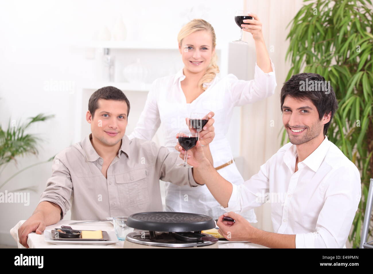 Friends enjoying a raclette Stock Photo - Alamy