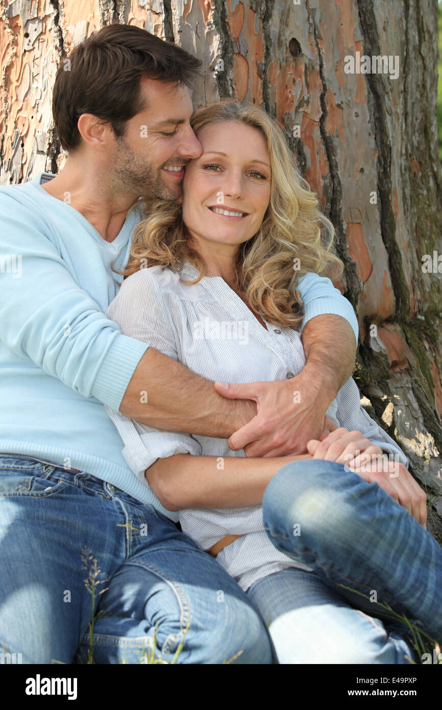 Couple cuddling in front of a tree Stock Photo - Alamy