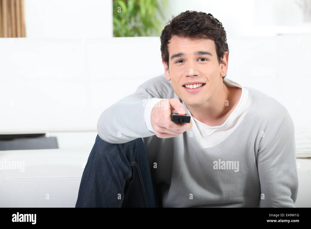Young man with TV remote Stock Photo - Alamy