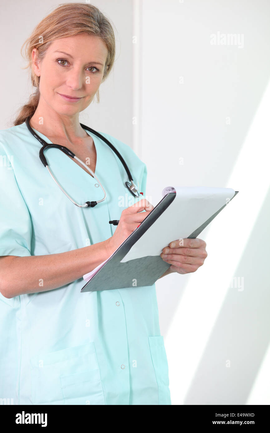 Nurse writing on clip-board Stock Photo - Alamy