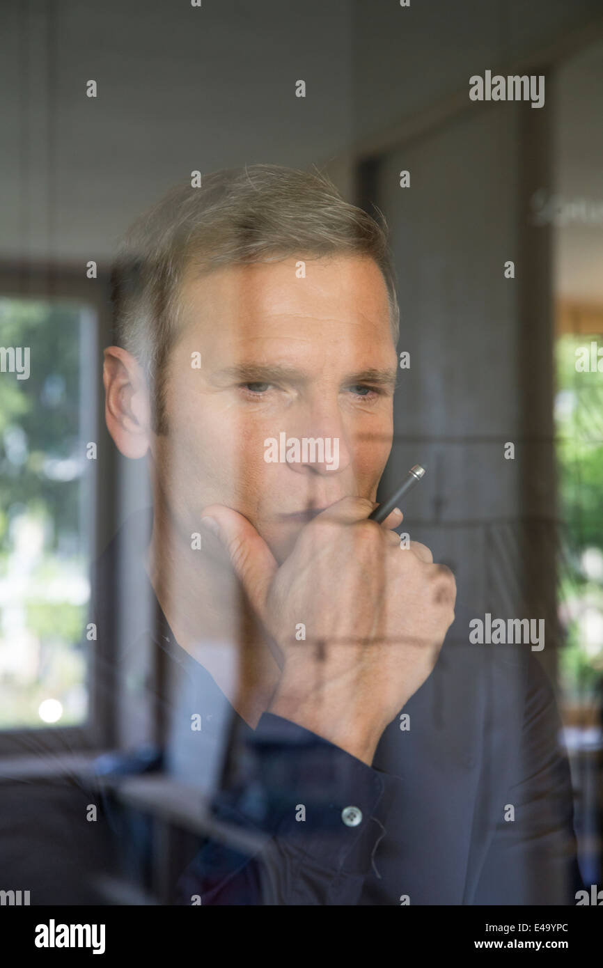 Portrait of pensive business man behind glass pane Stock Photo - Alamy