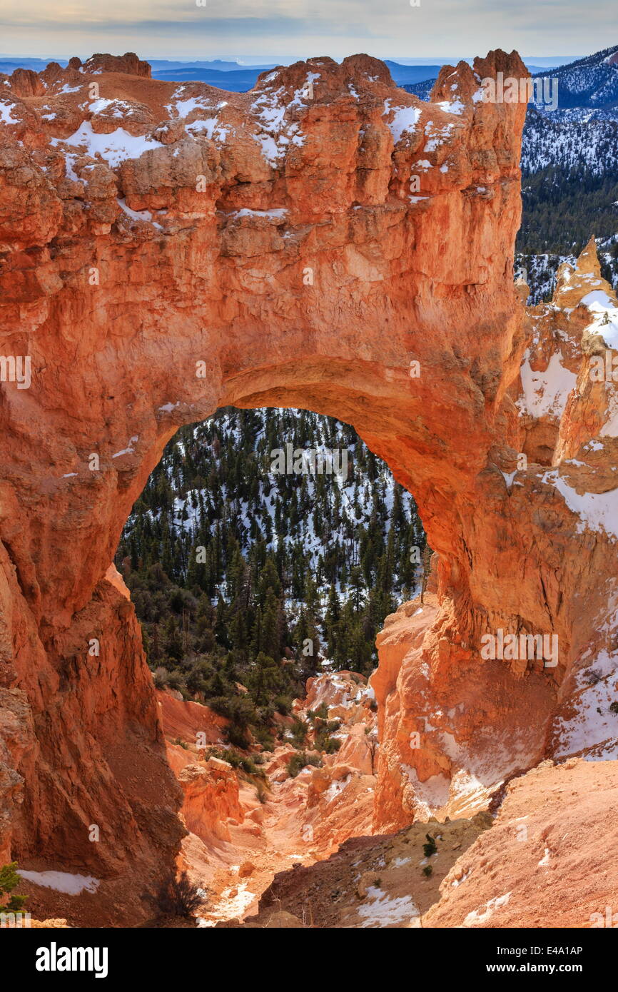 Red-hued limestone arch lit by morning sun with snow in winter at ...