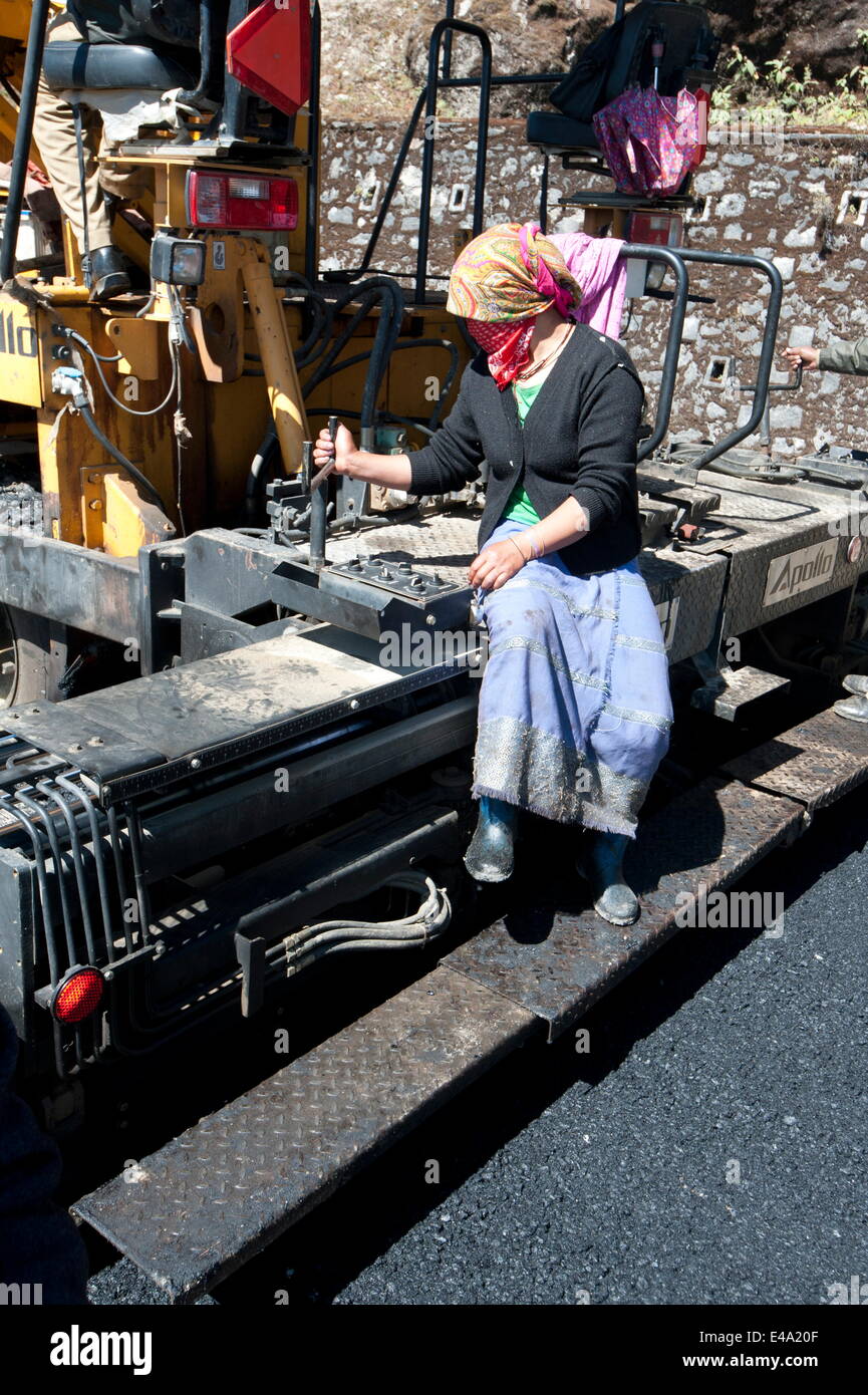 Female road worker in charge of tar spreading machine on hill roads ...