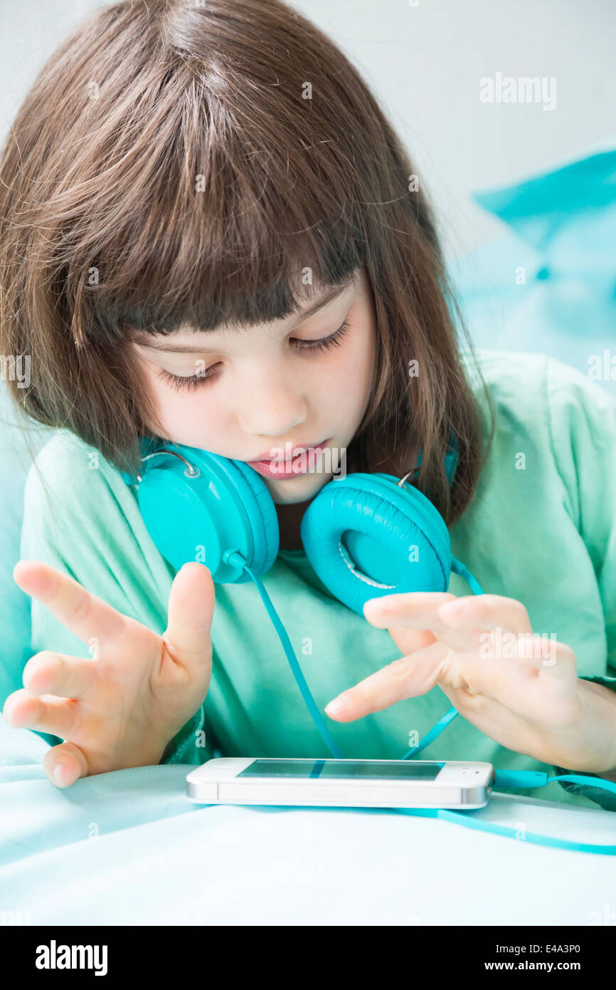 Portrait of little girl with headphones using smartphone Stock Photo ...