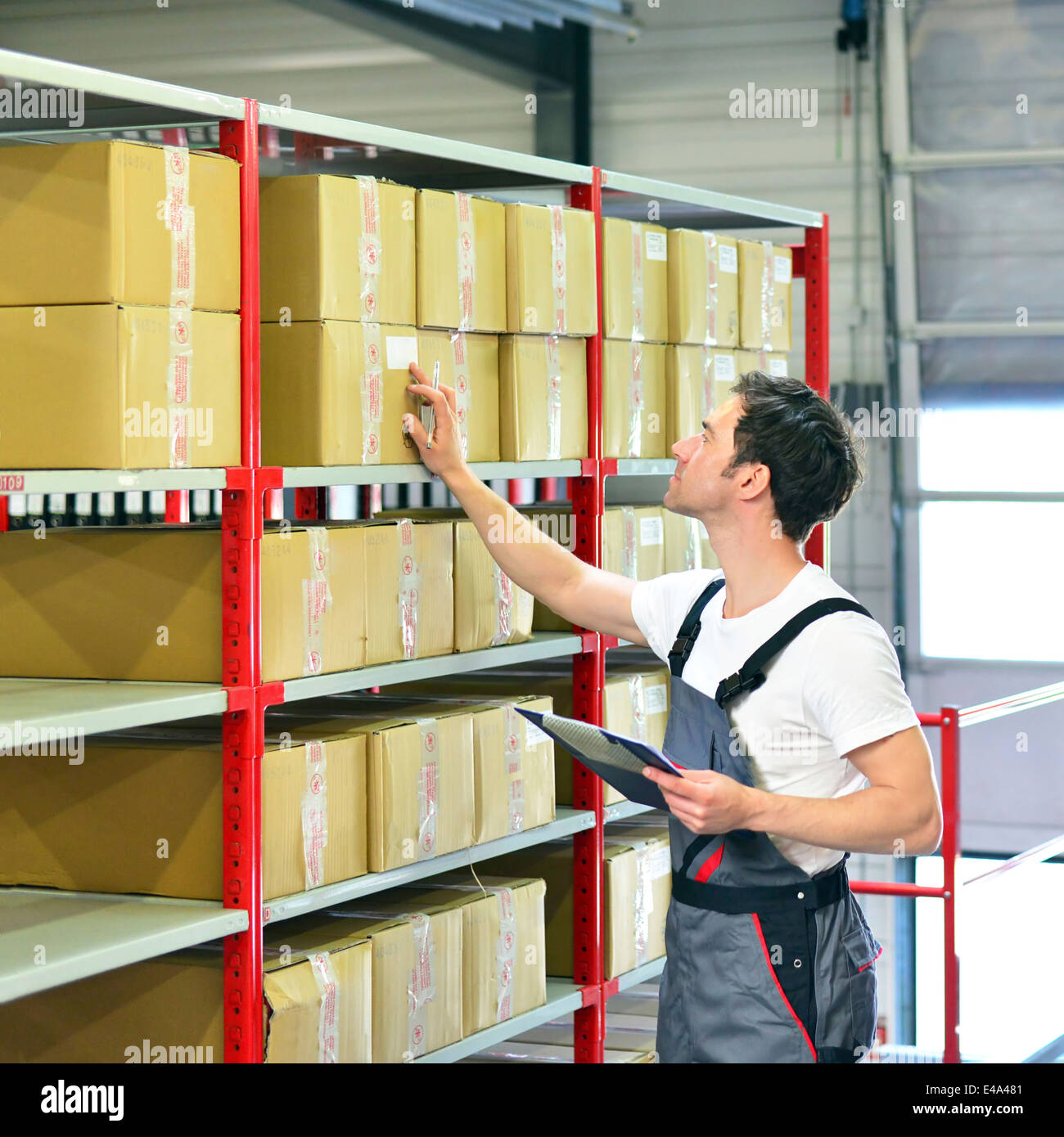 Worker in warehouse controlling goods Stock Photo - Alamy