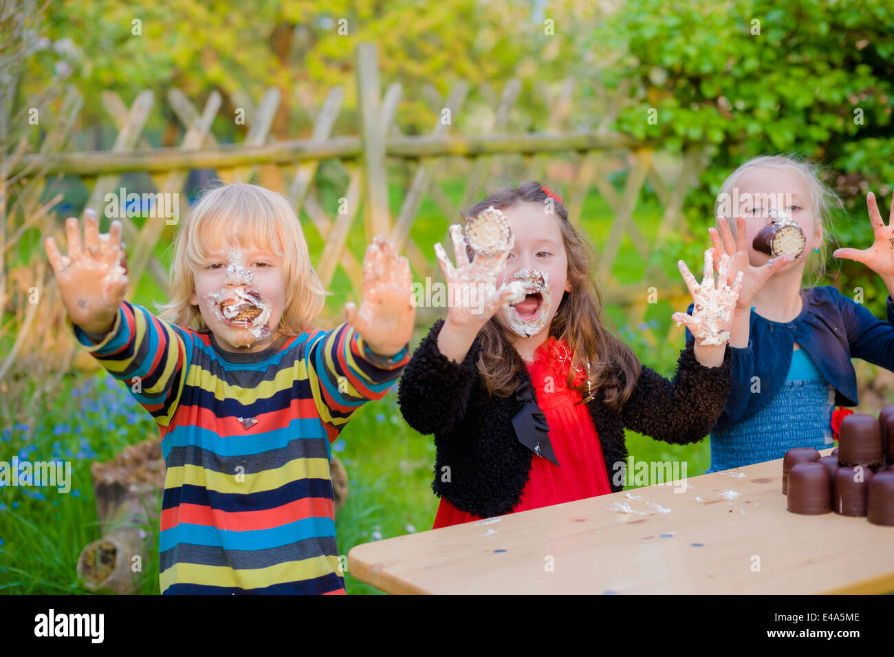 Three children making eating contest with chocolate marshmallows Stock ...