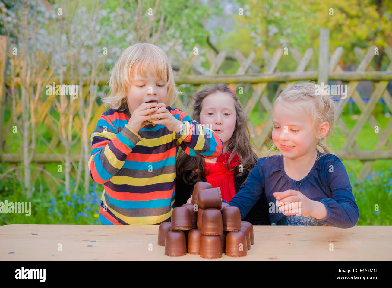Three children making eating contest with chocolate marshmallows Stock ...