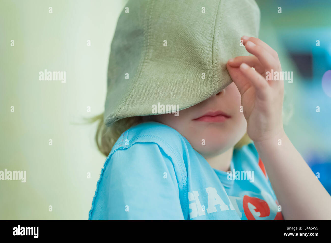Blond hiding his face with a cap Stock Photo - Alamy