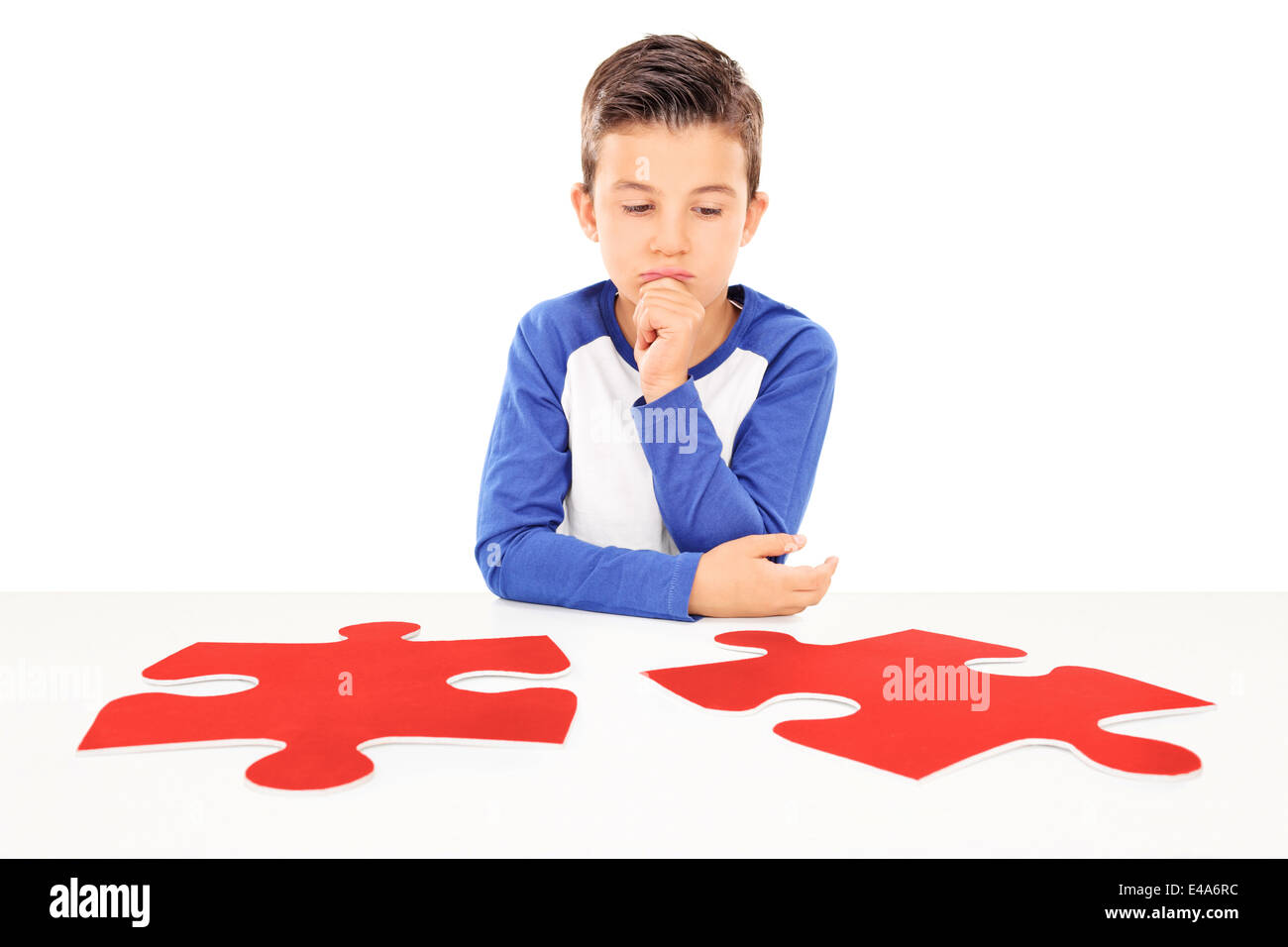 Pensive boy looking at two pieces of puzzle Stock Photo - Alamy