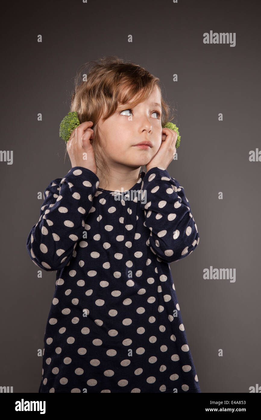 Portrait of little girl holding broccoli on his ears Stock Photo - Alamy