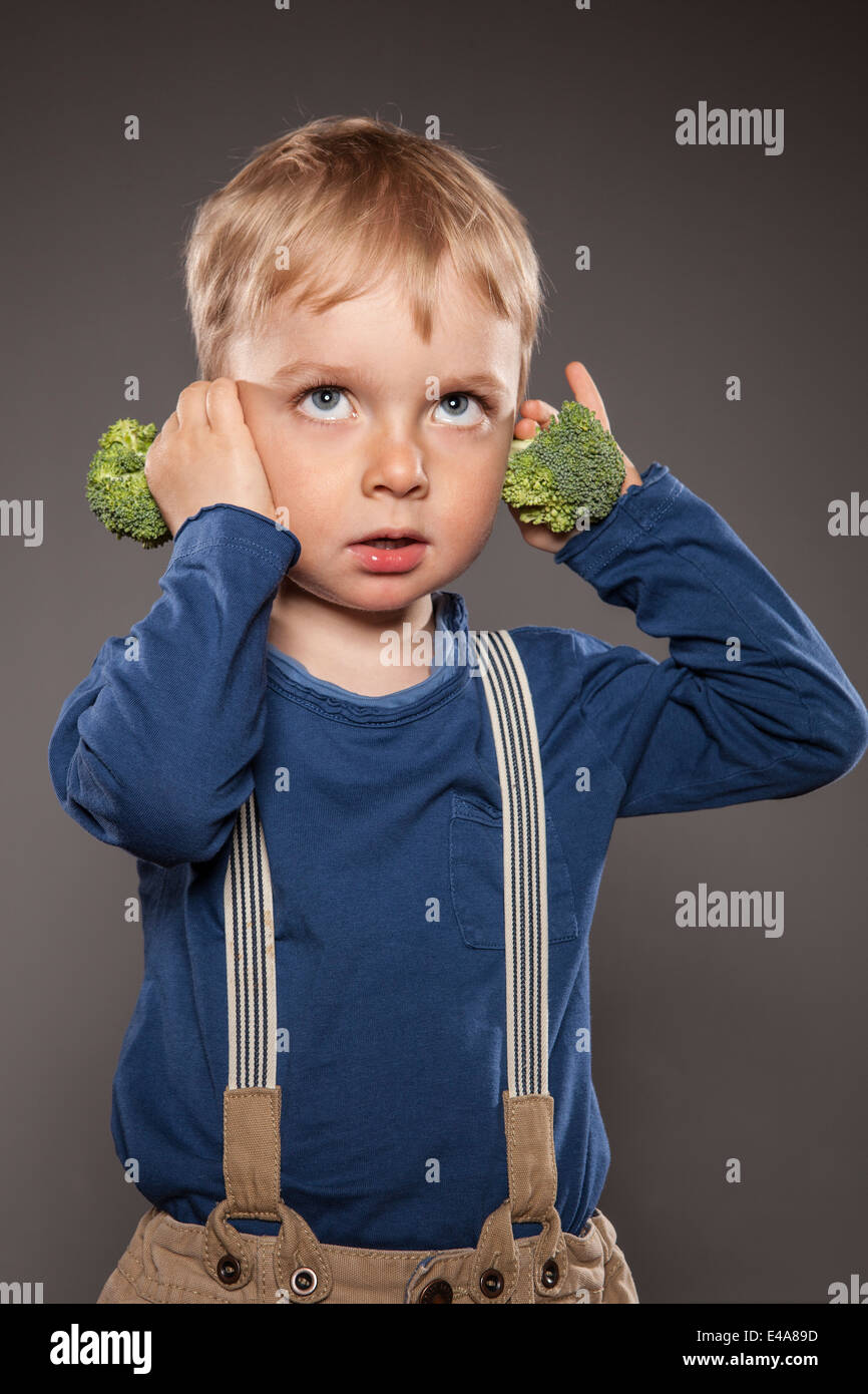 Portrait of little boy holding broccoli on his ears Stock Photo - Alamy