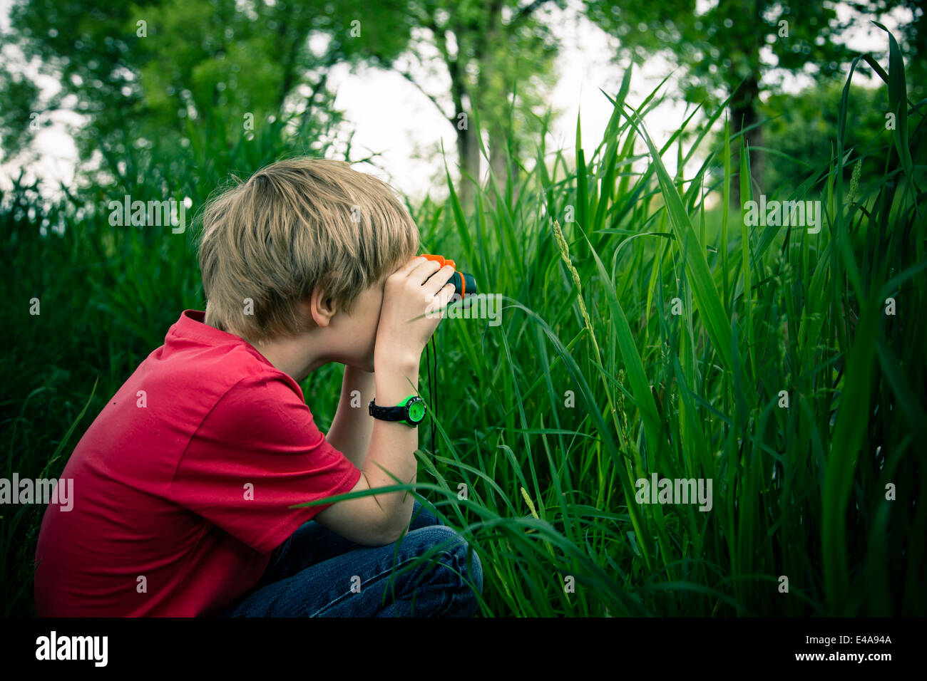 Little boy sitting on meadow watching something with binocular Stock ...