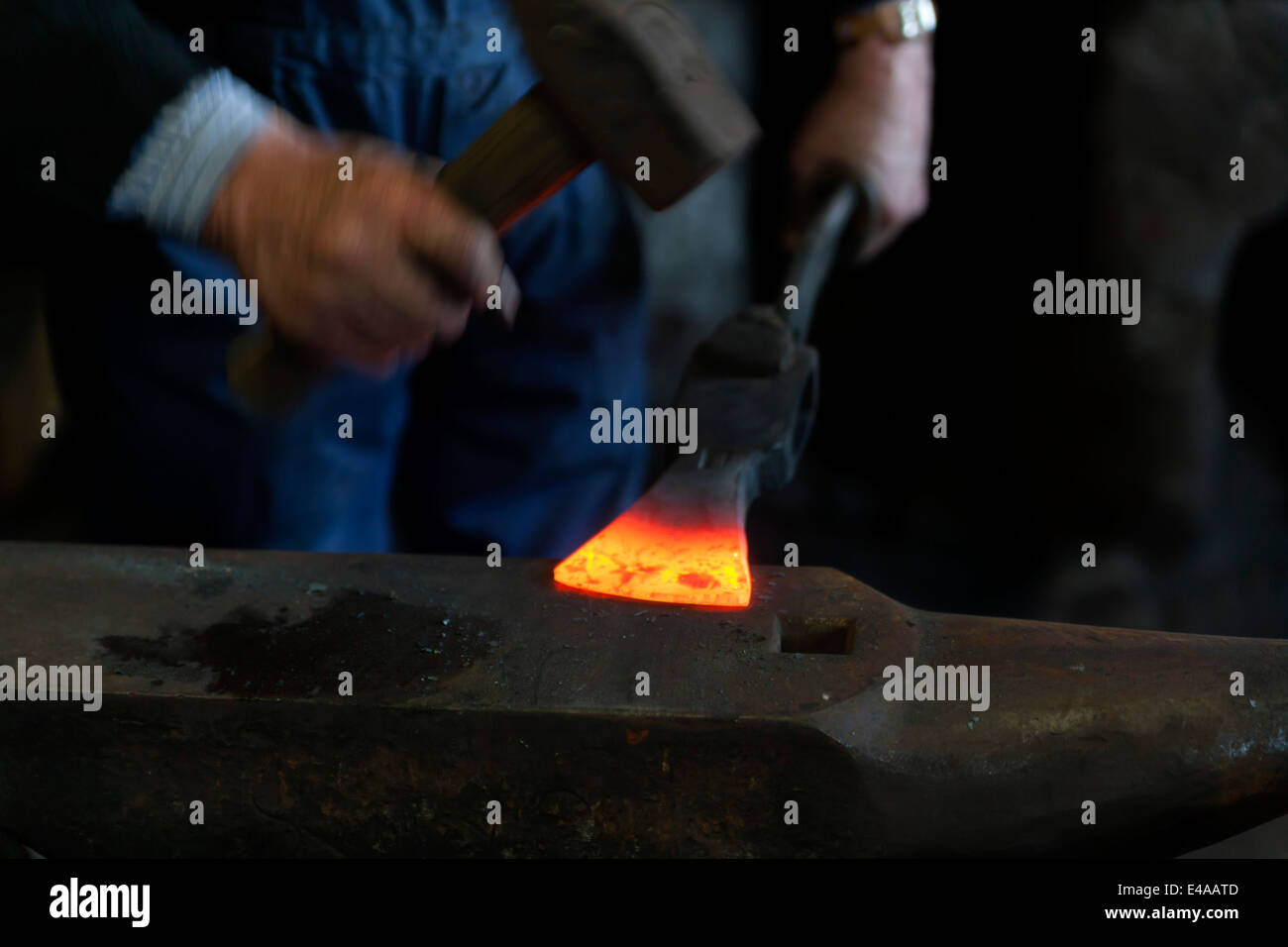 Germany, Bavaria, Josefsthal, blacksmith beating glowing axe on anvil ...
