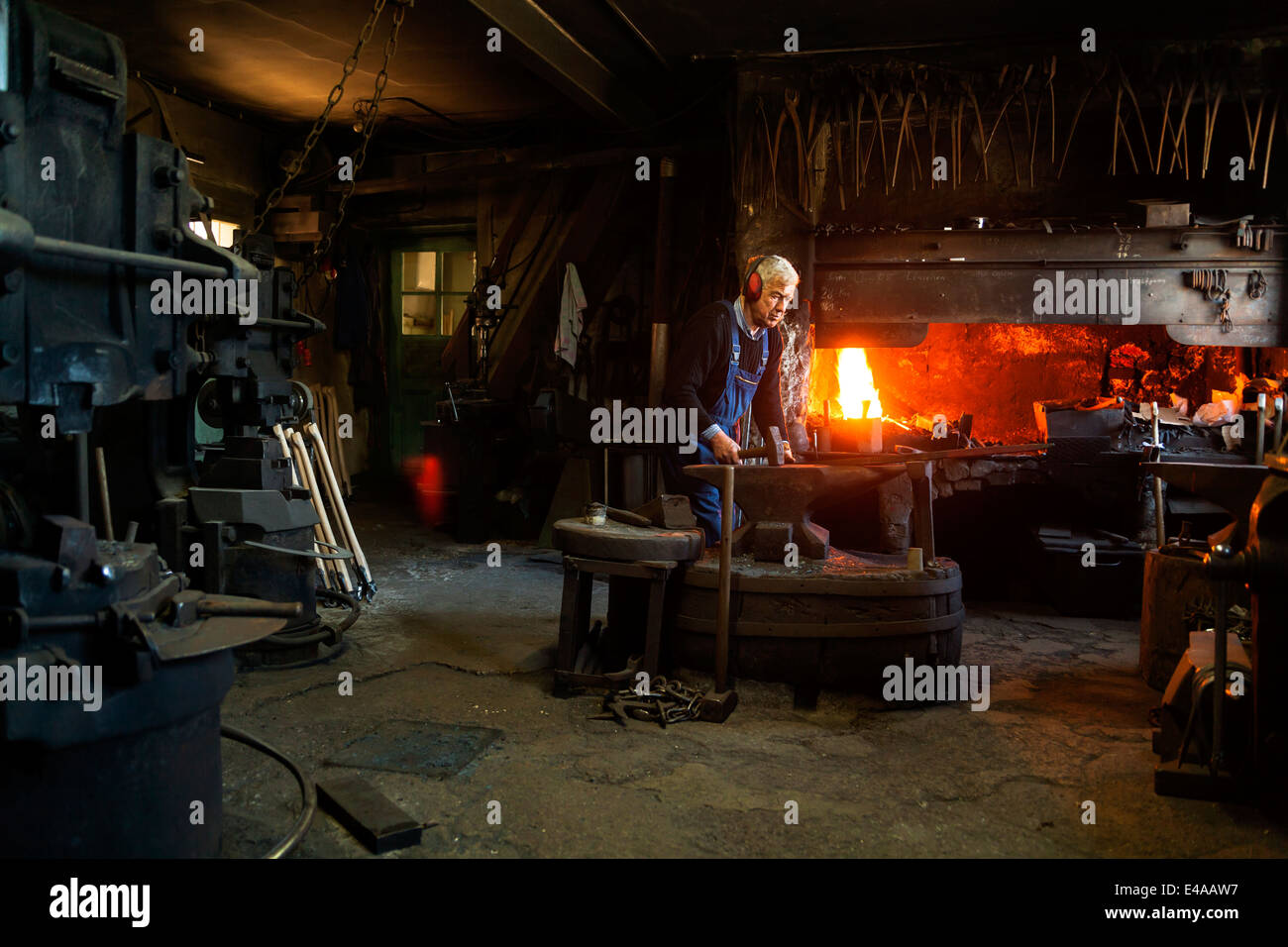 Germany, Bavaria, Josefsthal, senior blacksmith at work in historic ...
