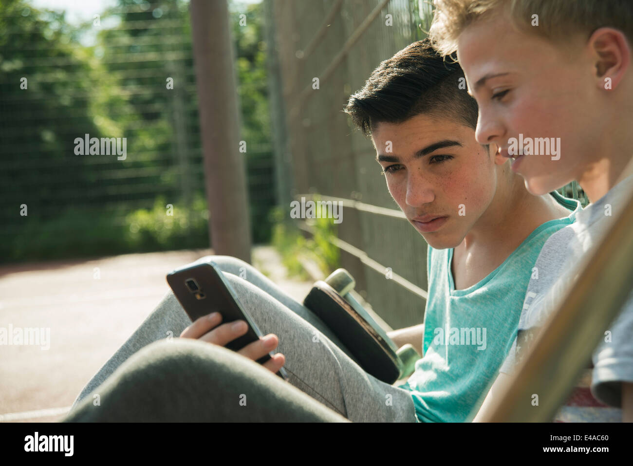 Two friends with cell phone and skateboard Stock Photo - Alamy