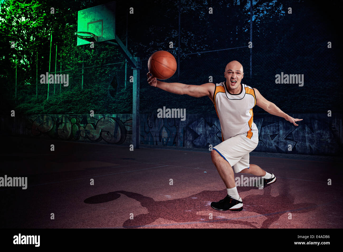 Basketball player on a street basketball court at night Stock Photo - Alamy