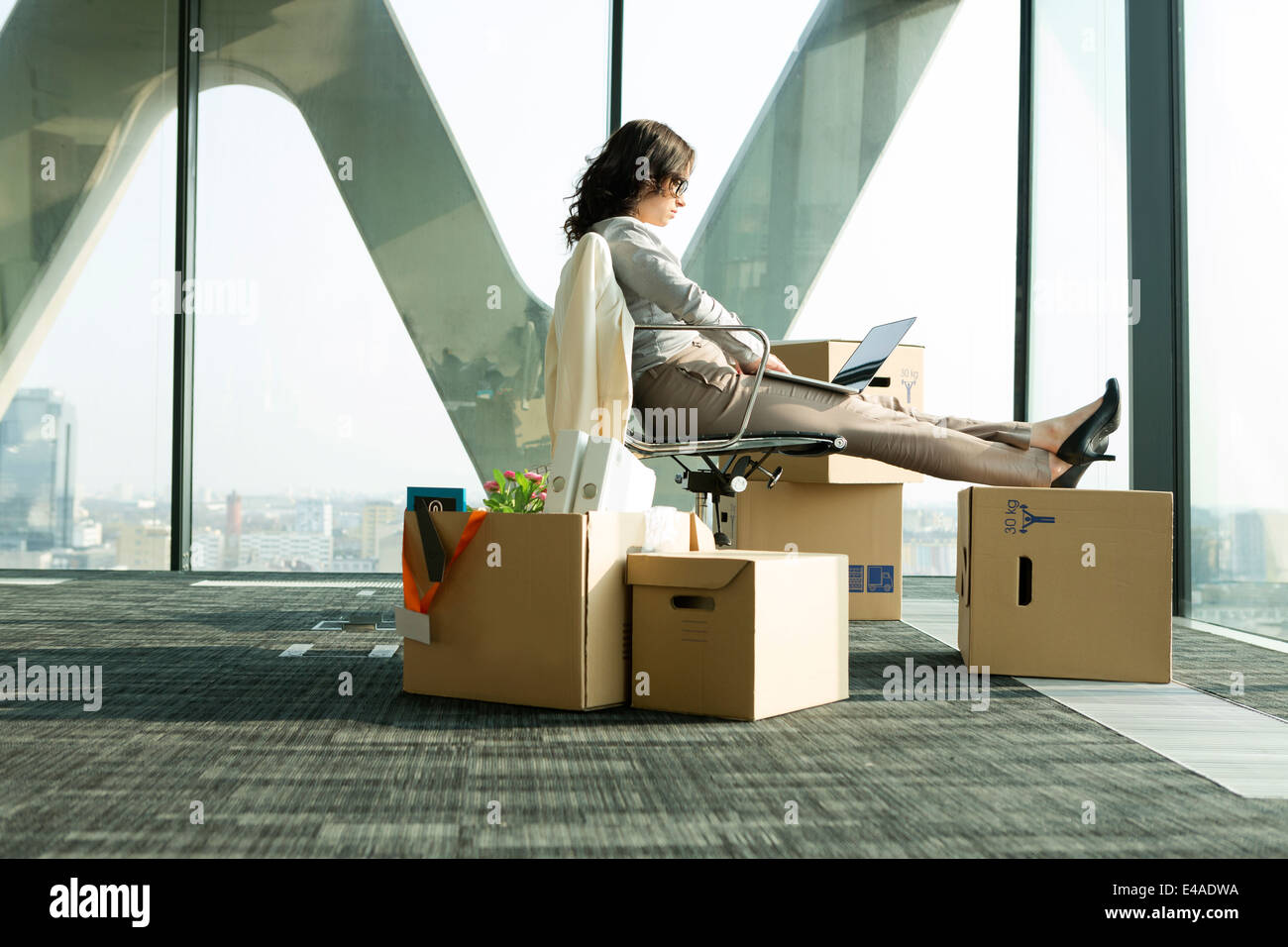 Businesswoman using laptop with feet on cardboard boxes Stock Photo - Alamy