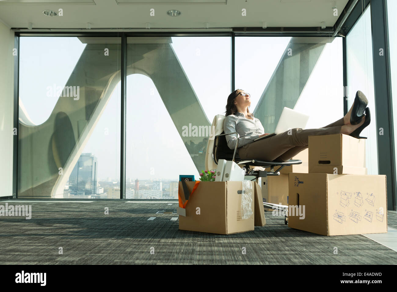 Businesswoman using laptop with feet on cardboard boxes Stock Photo - Alamy